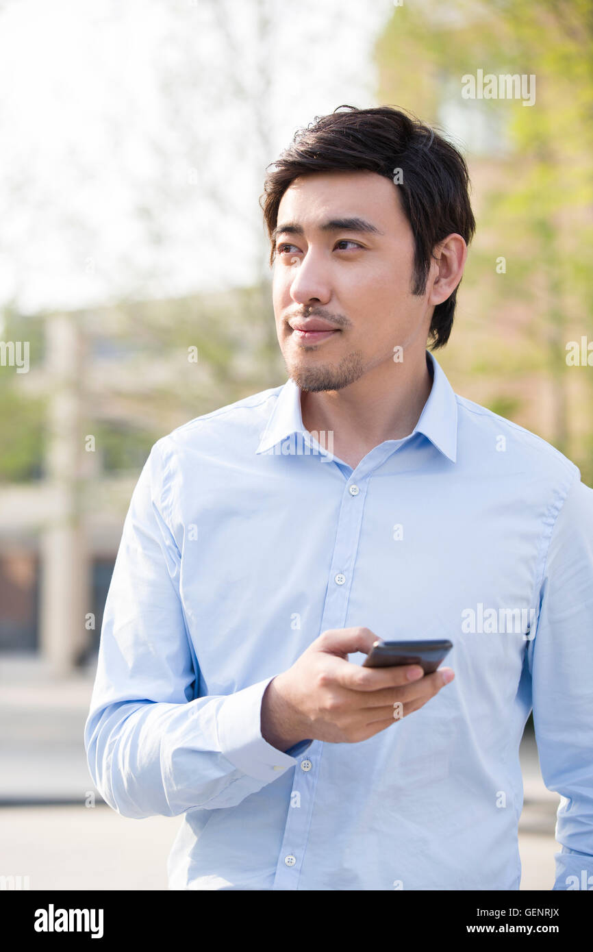Young Chinese man holding a smart phone Stock Photo - Alamy