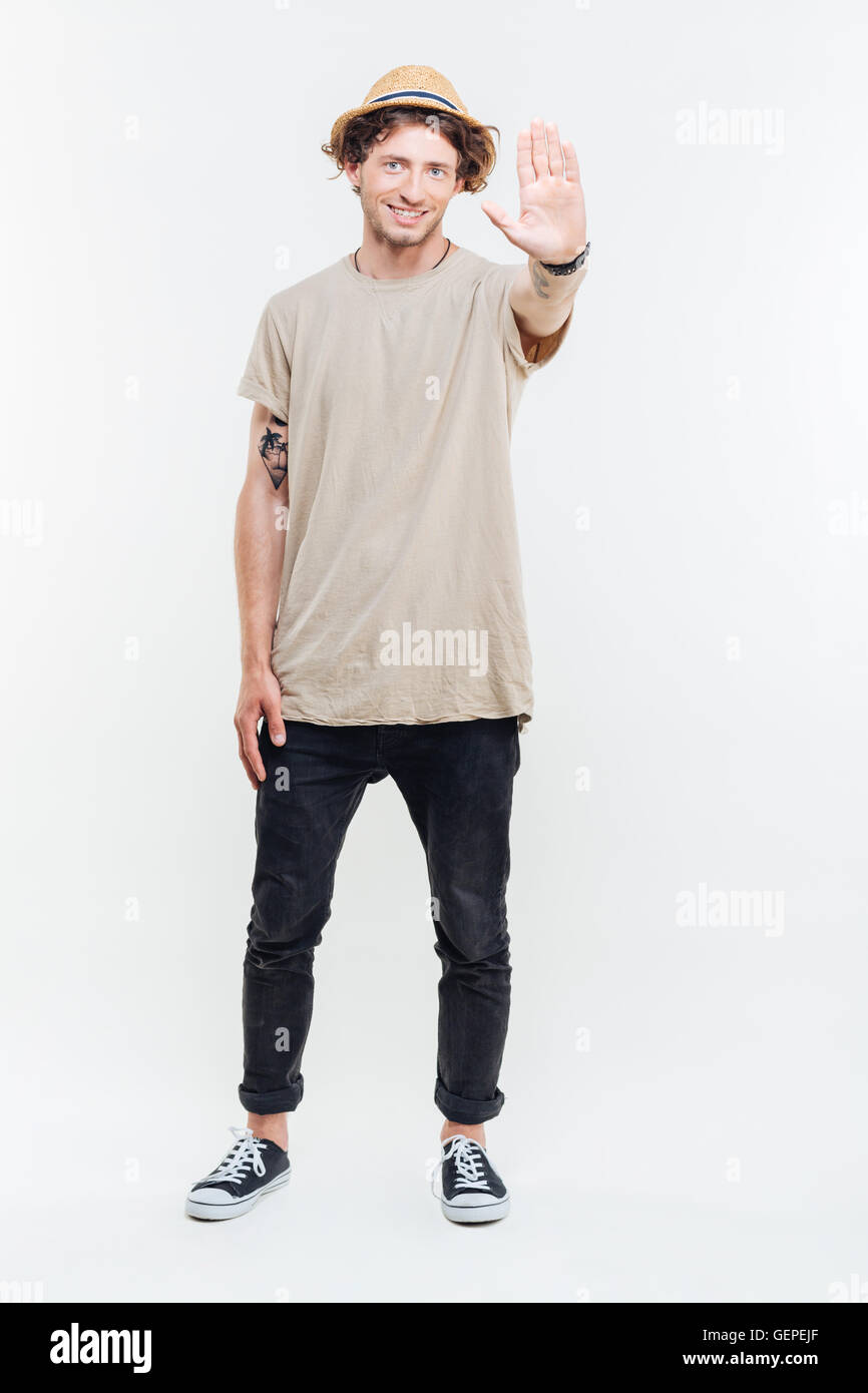 Full length portrait of a smiling man showing stop sign with palm ...