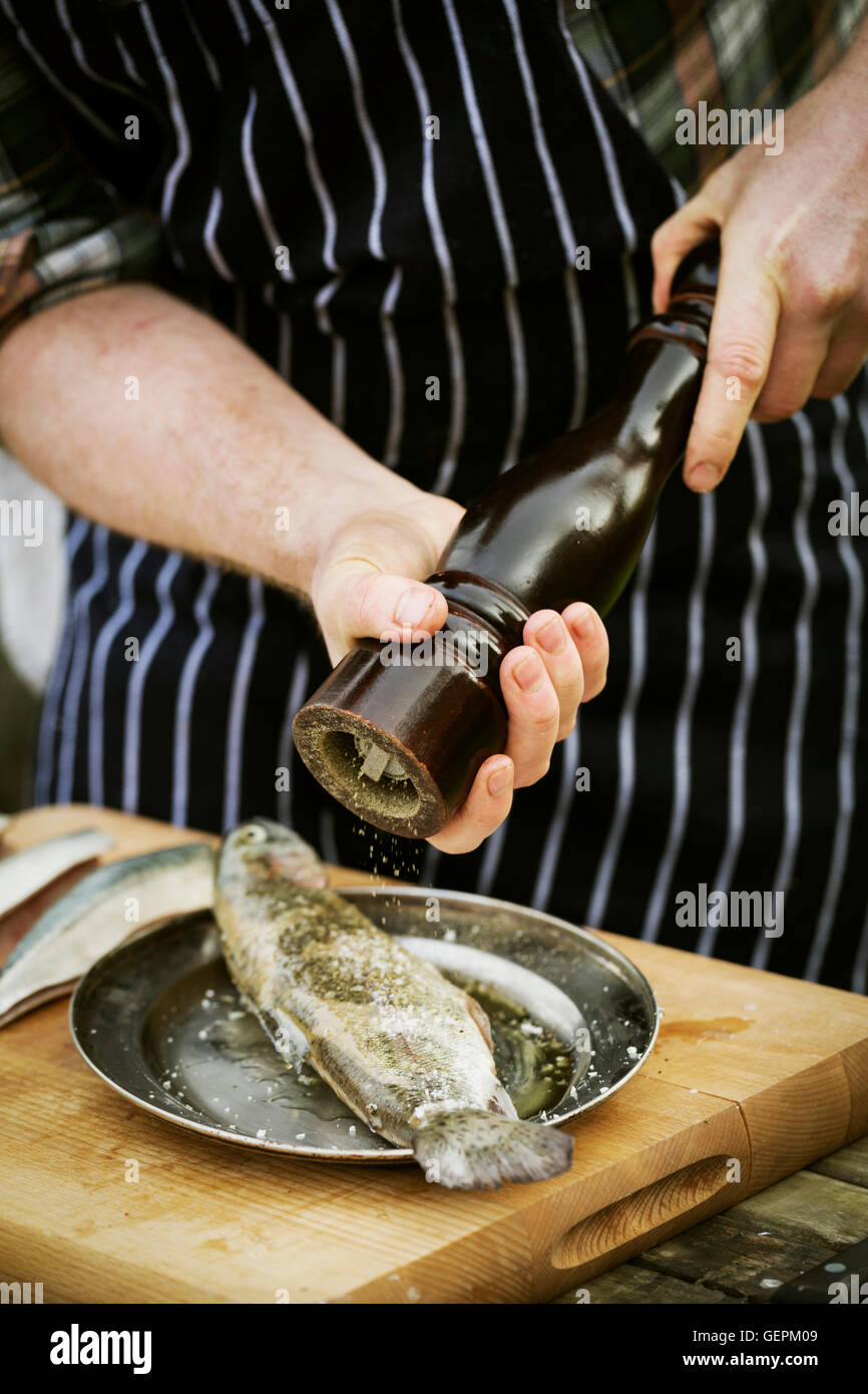 Chef using a salt mill, grinding salt onto a fresh fish Stock Photo - Alamy