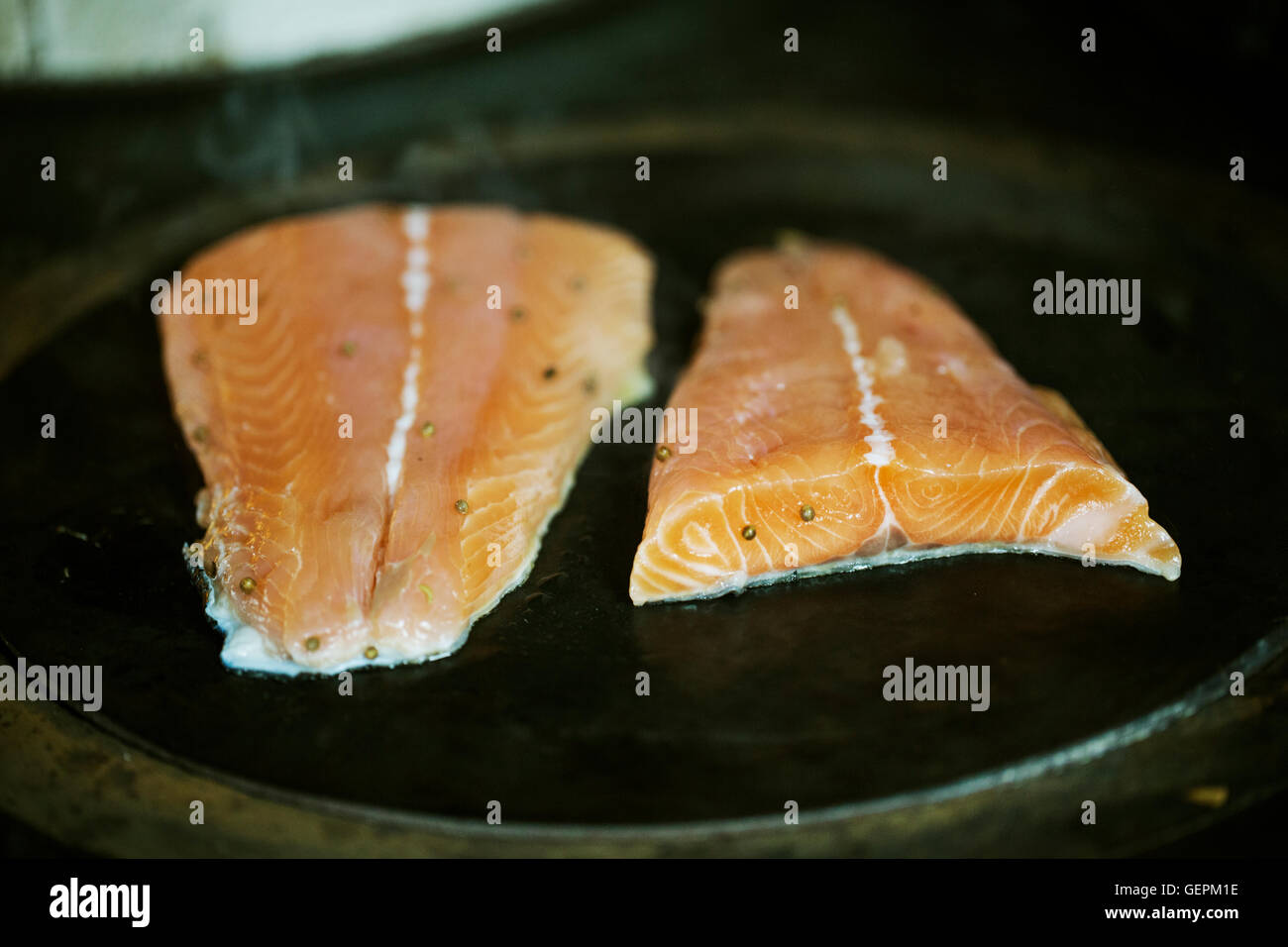 Close up of two fish fillets being fried on a stove Stock Photo - Alamy