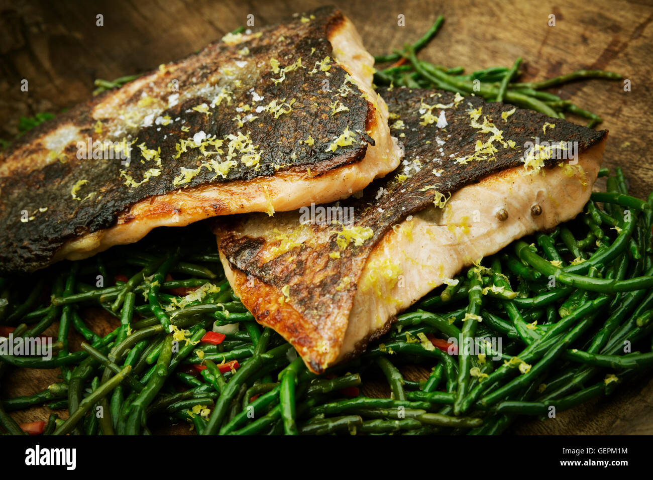 Close up of grilled fish fillets with crispy skin on a bed of samphire ...