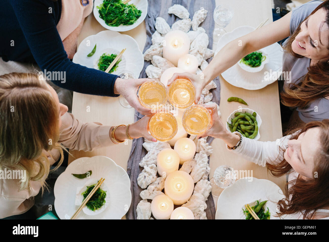 Overhead view of four people sharing a meal, plates of sushi and a ...