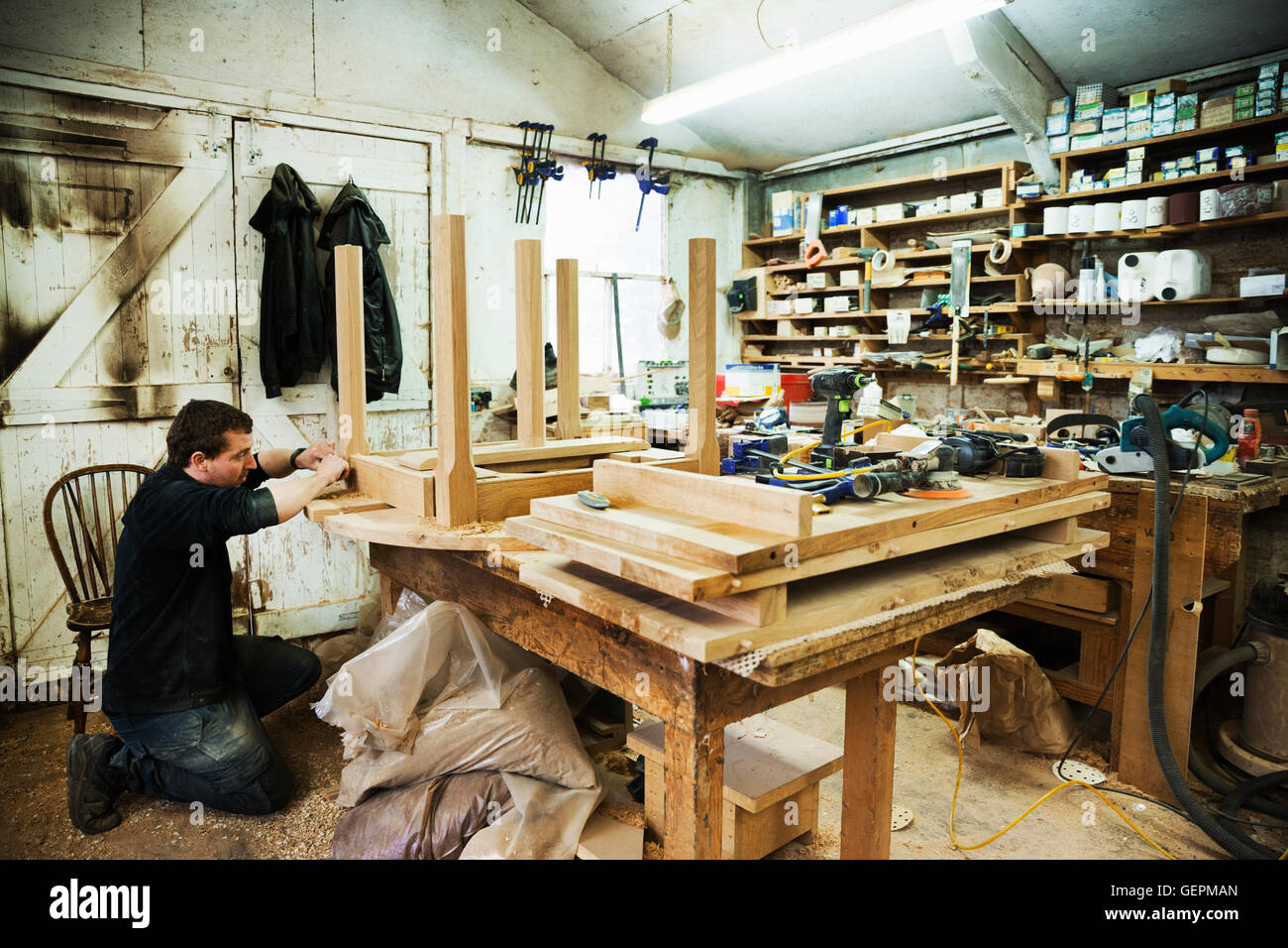 Man standing in a carpentry workshop, working on the skirting of a ...