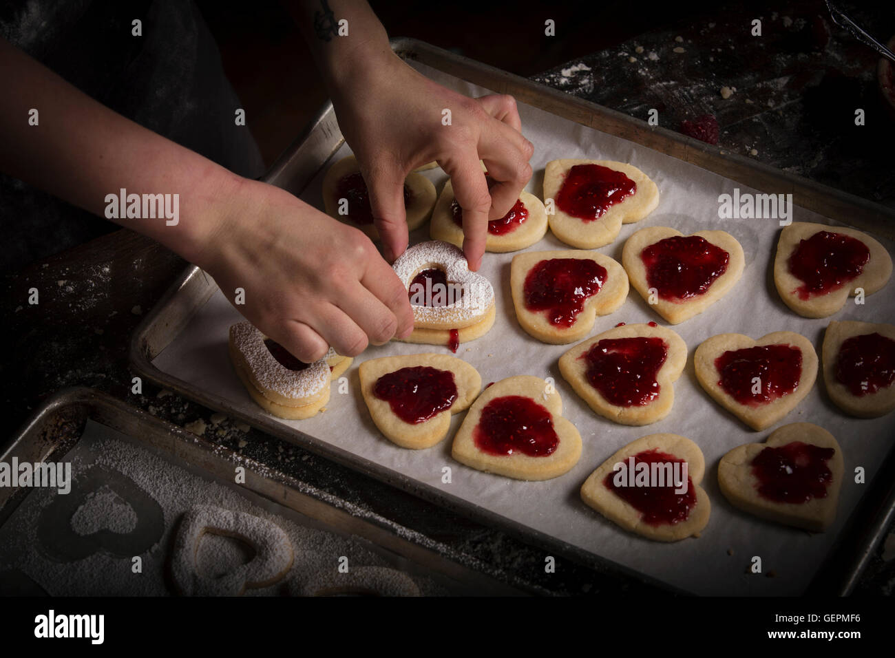 Valentine's Day baking, woman spreading raspberry jam on heart shaped ...