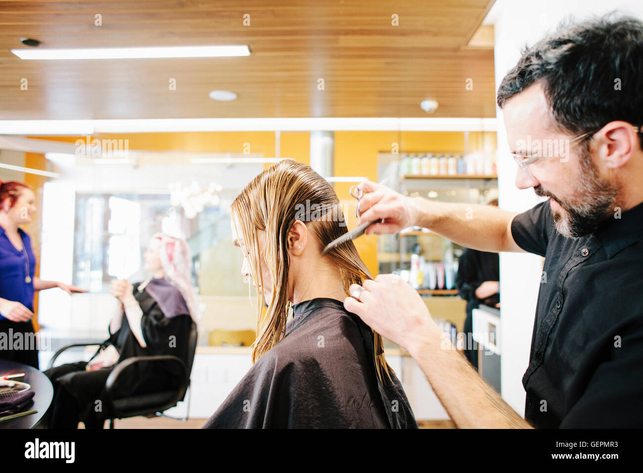 A hair stylist with a client, combing her long hair in sections Stock ...