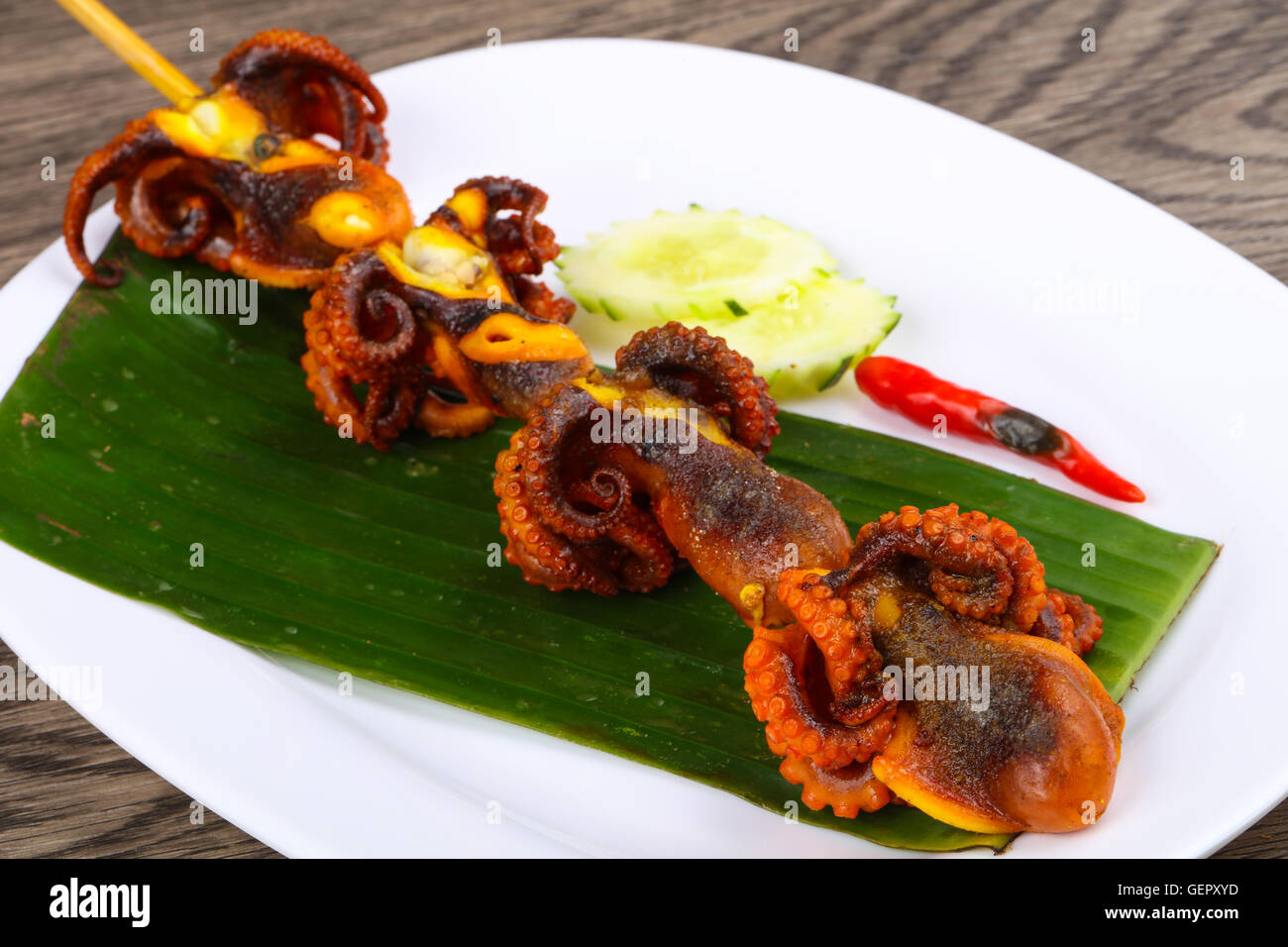Asian cuisine - Octopus skewer on banana leaves Stock Photo - Alamy
