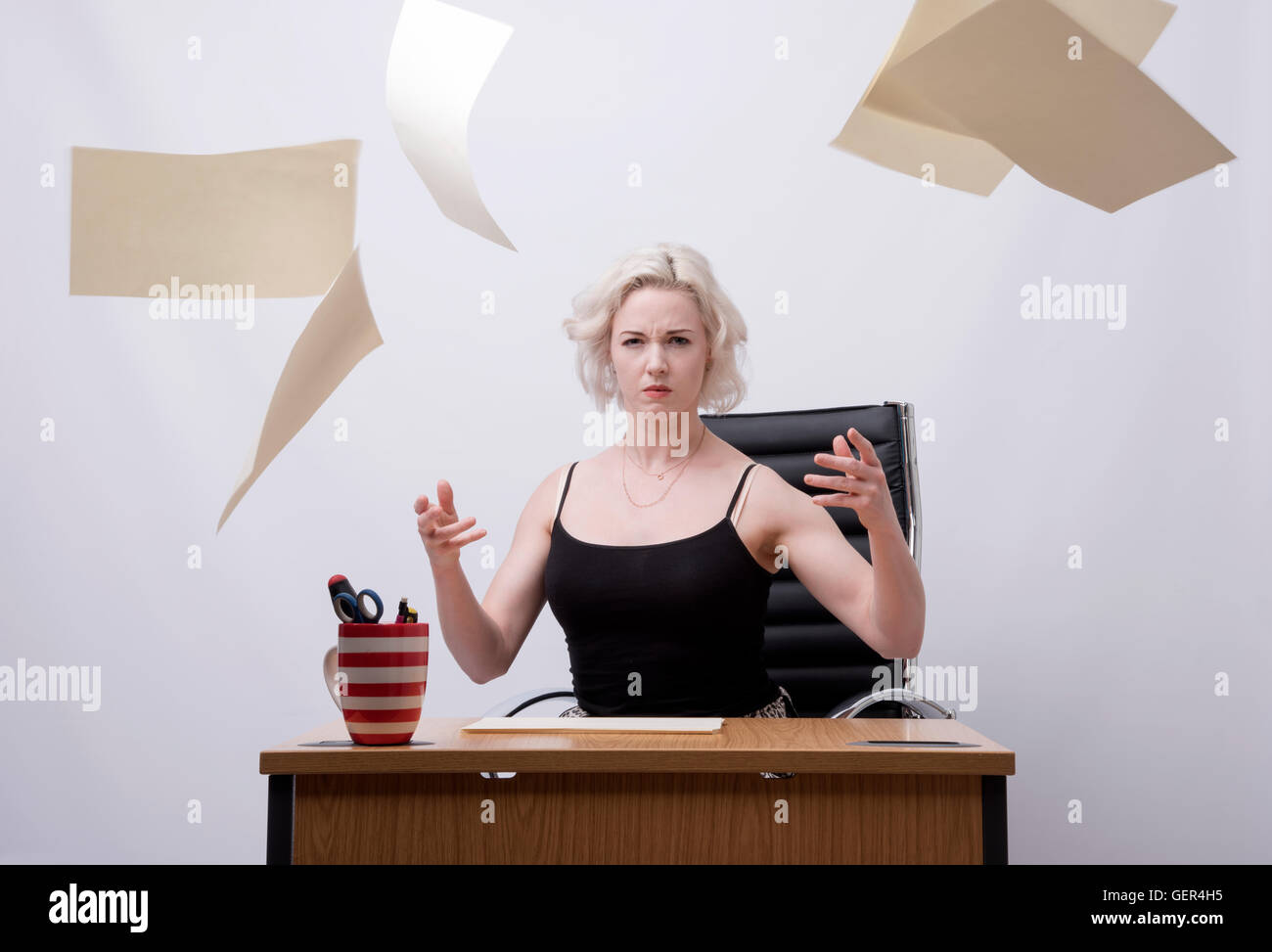 A stressed secretary throws paperwork into the air from her desk Stock ...