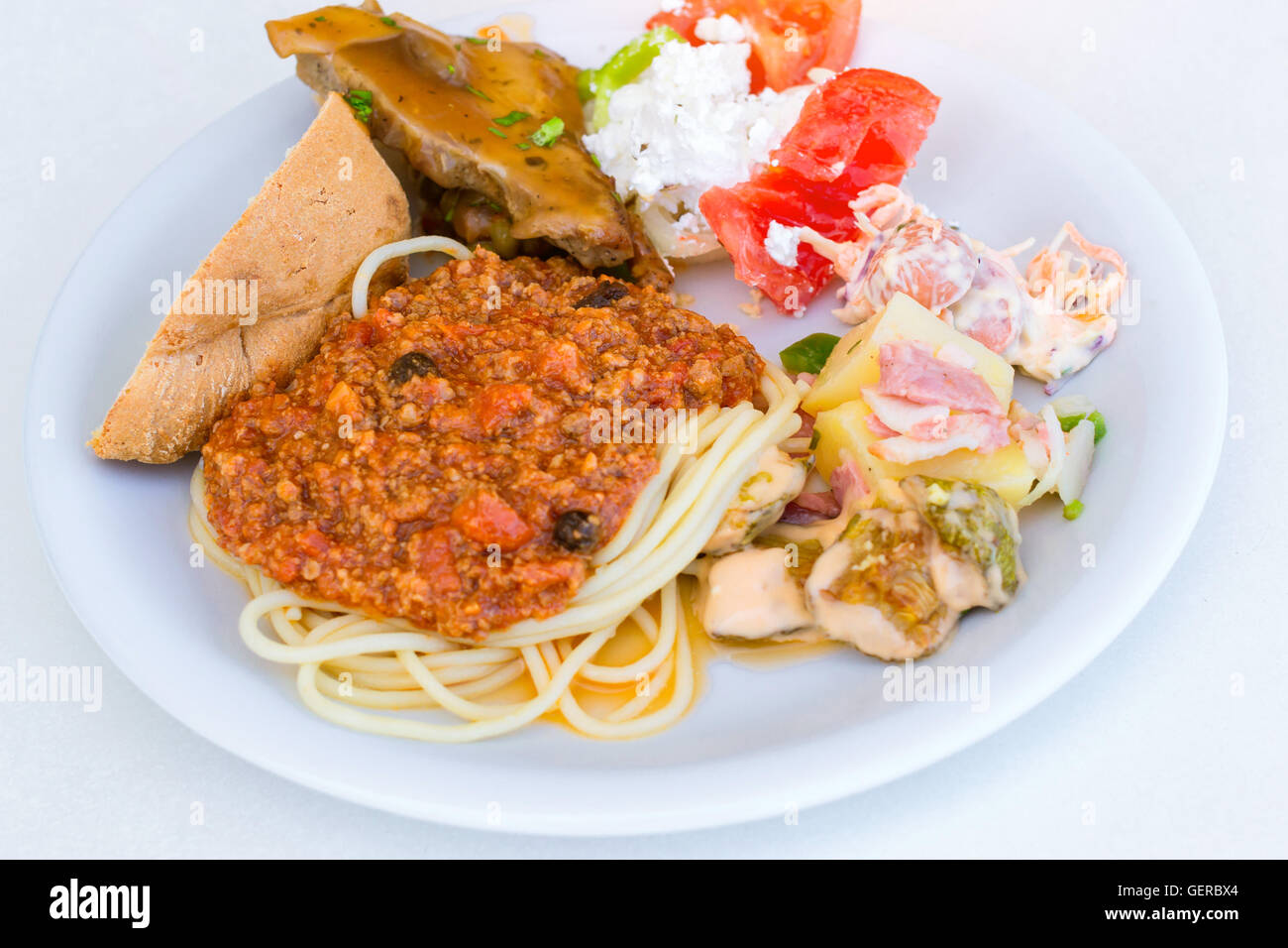 Spaghetti Bolognese with a Greek salad on a white plate. Bali, Rethymno ...