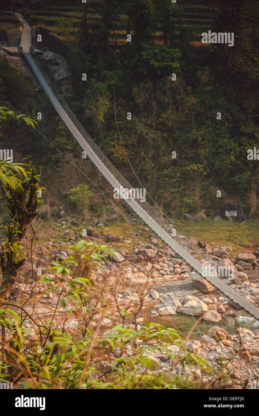 Unknown person crossing the long hanging bridge over mountain river in ...