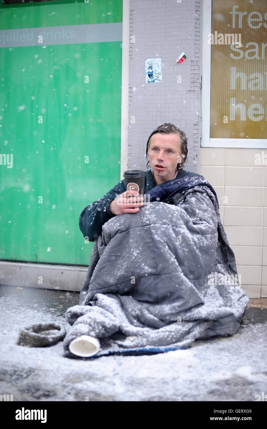 A homeless man sits in the street in Cardiff City Centre during heavy ...