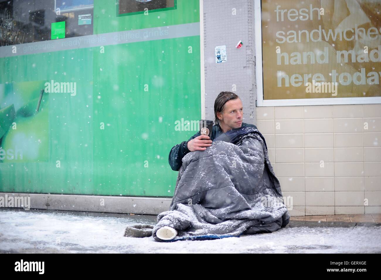 A homeless man sits in the street in Cardiff City Centre during heavy ...