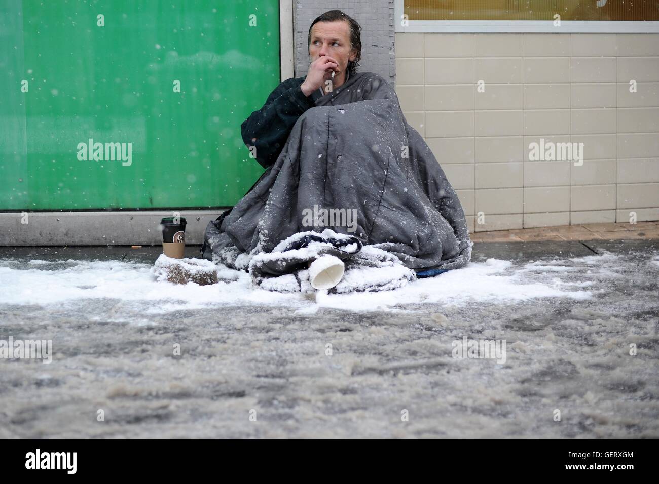 A homeless man sits in the street in Cardiff City Centre during heavy ...