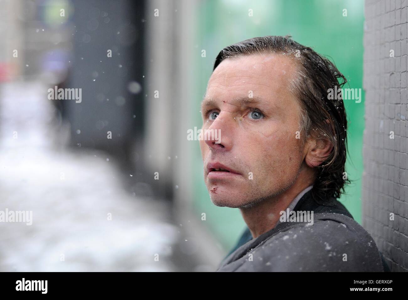 A homeless man sits in the street in Cardiff City Centre during heavy ...