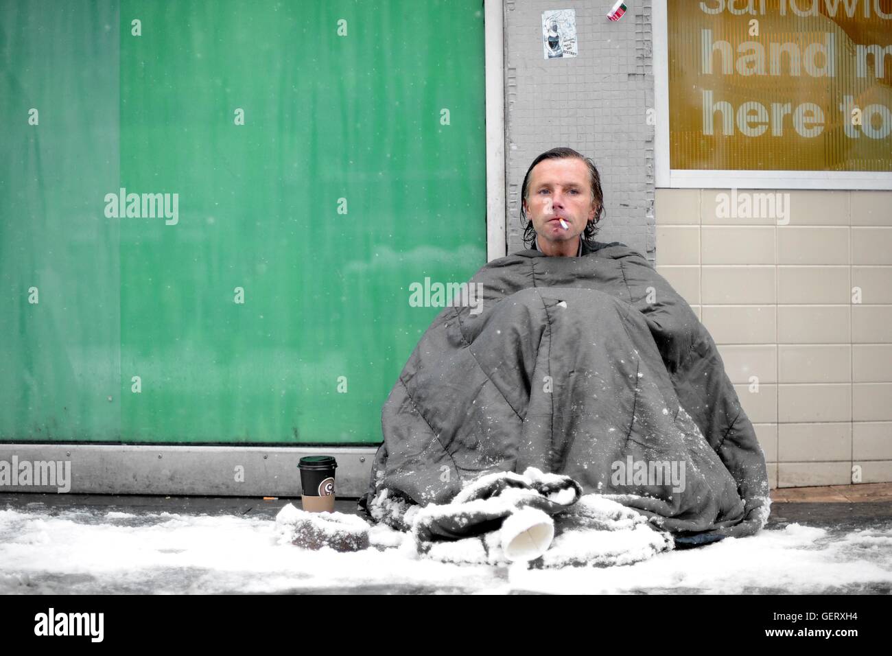 A homeless man sits in the street in Cardiff City Centre during heavy ...