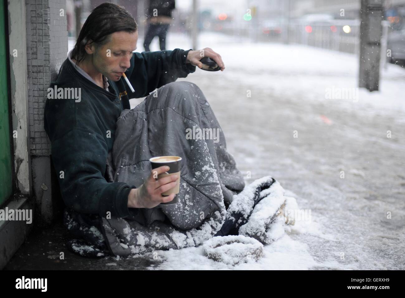 A homeless man sits in the street in Cardiff City Centre during heavy ...