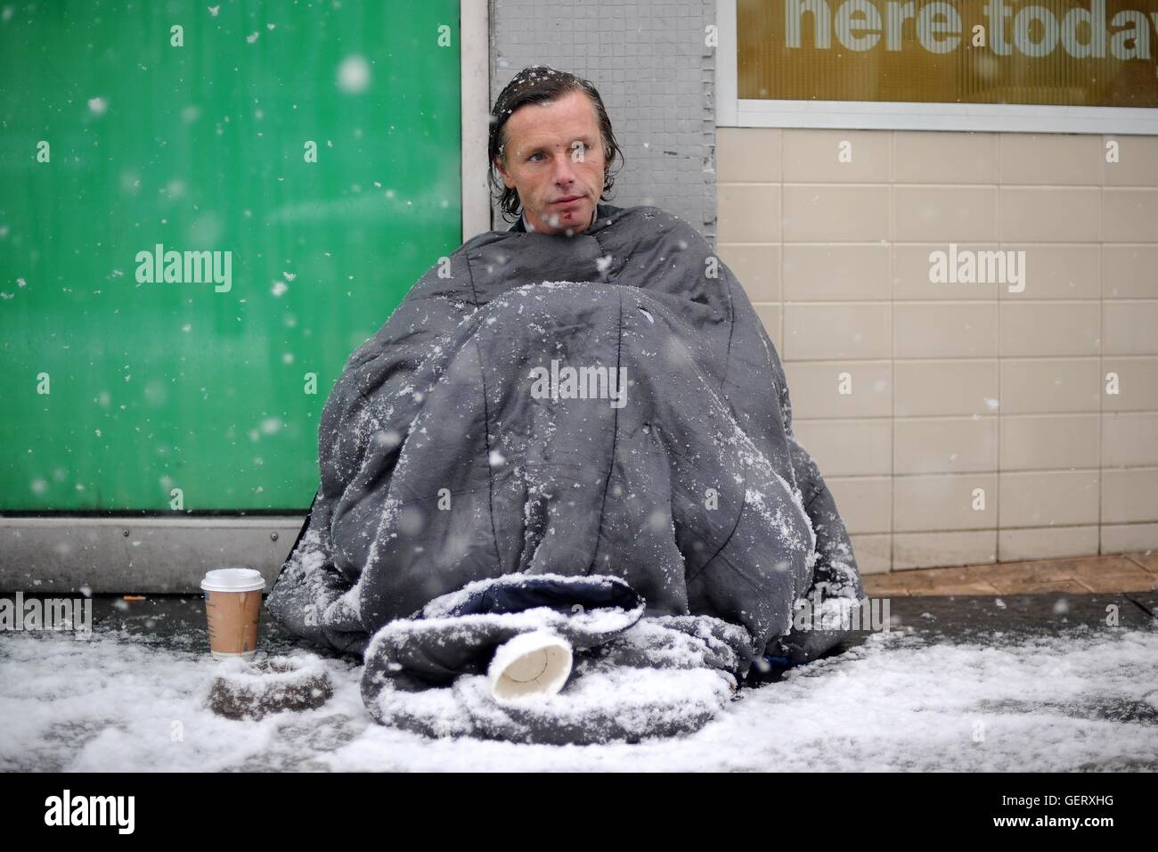 A homeless man sits in the street in Cardiff City Centre during heavy ...