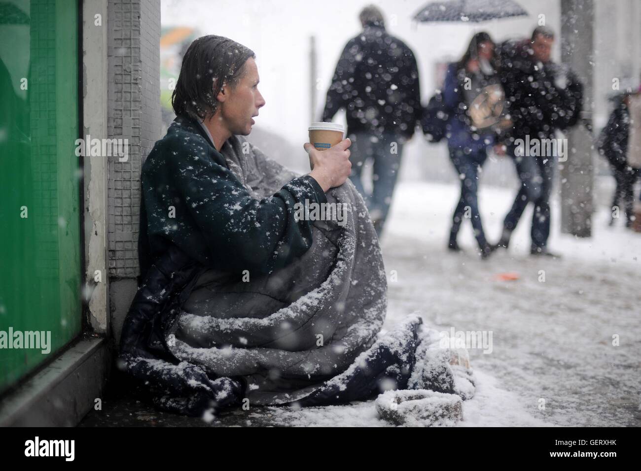 A homeless man sits in the street in Cardiff City Centre during heavy ...