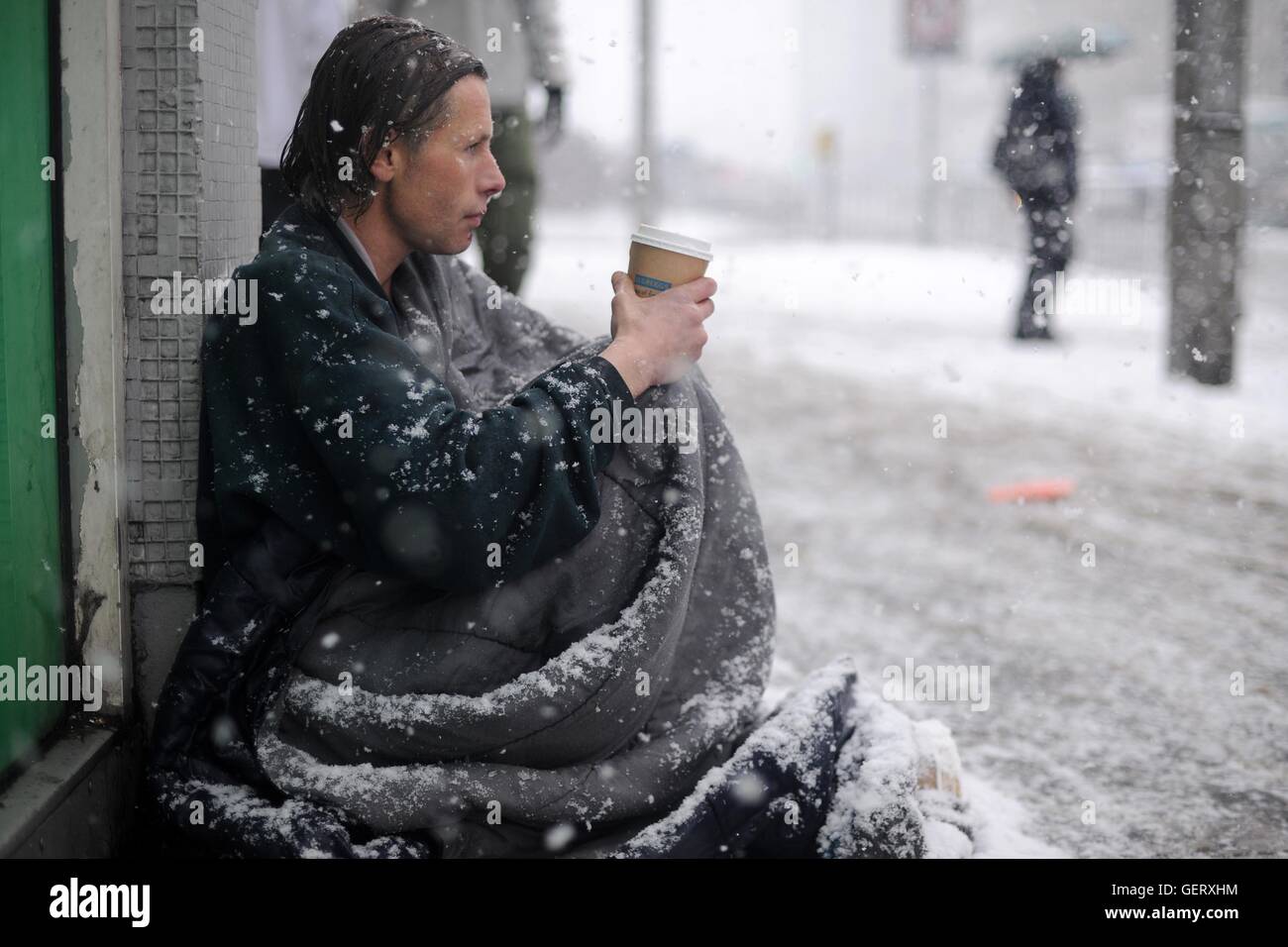 A homeless man sits in the street in Cardiff City Centre during heavy ...
