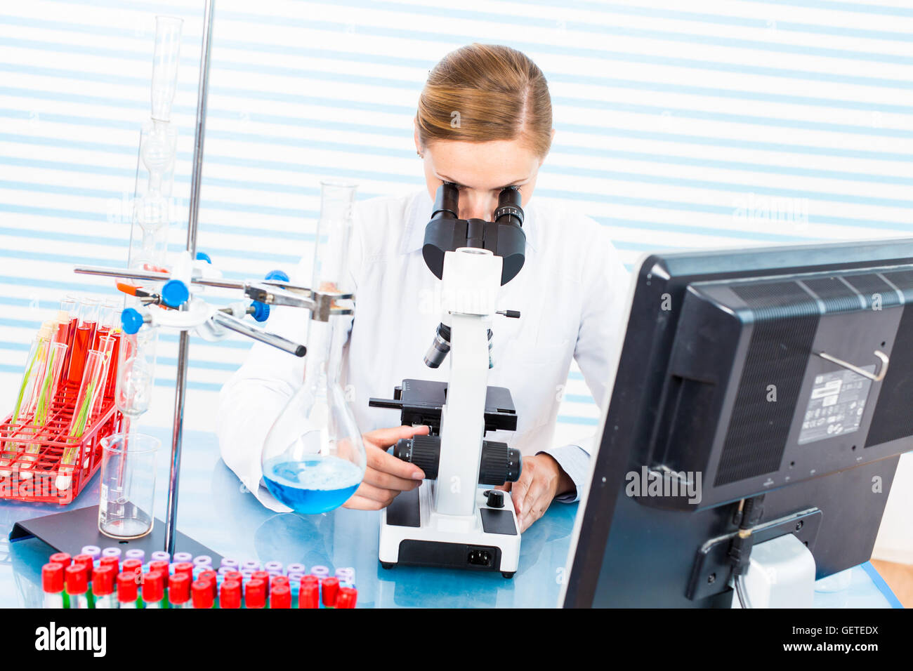 Woman in a medical lab technician with a microscope and a monitor Stock ...