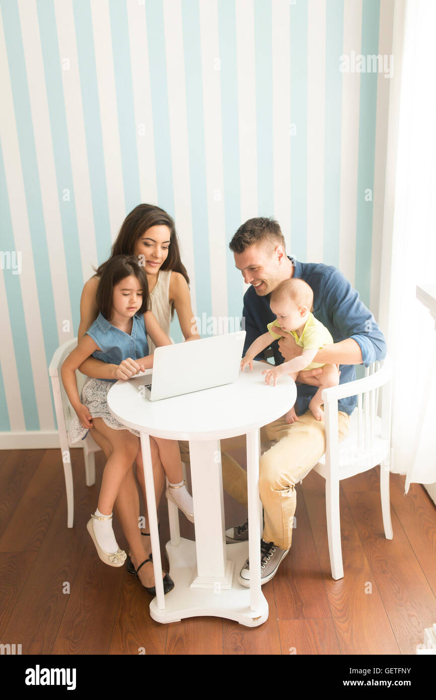 Young parents with daughers by the table with laptop in the room Stock ...