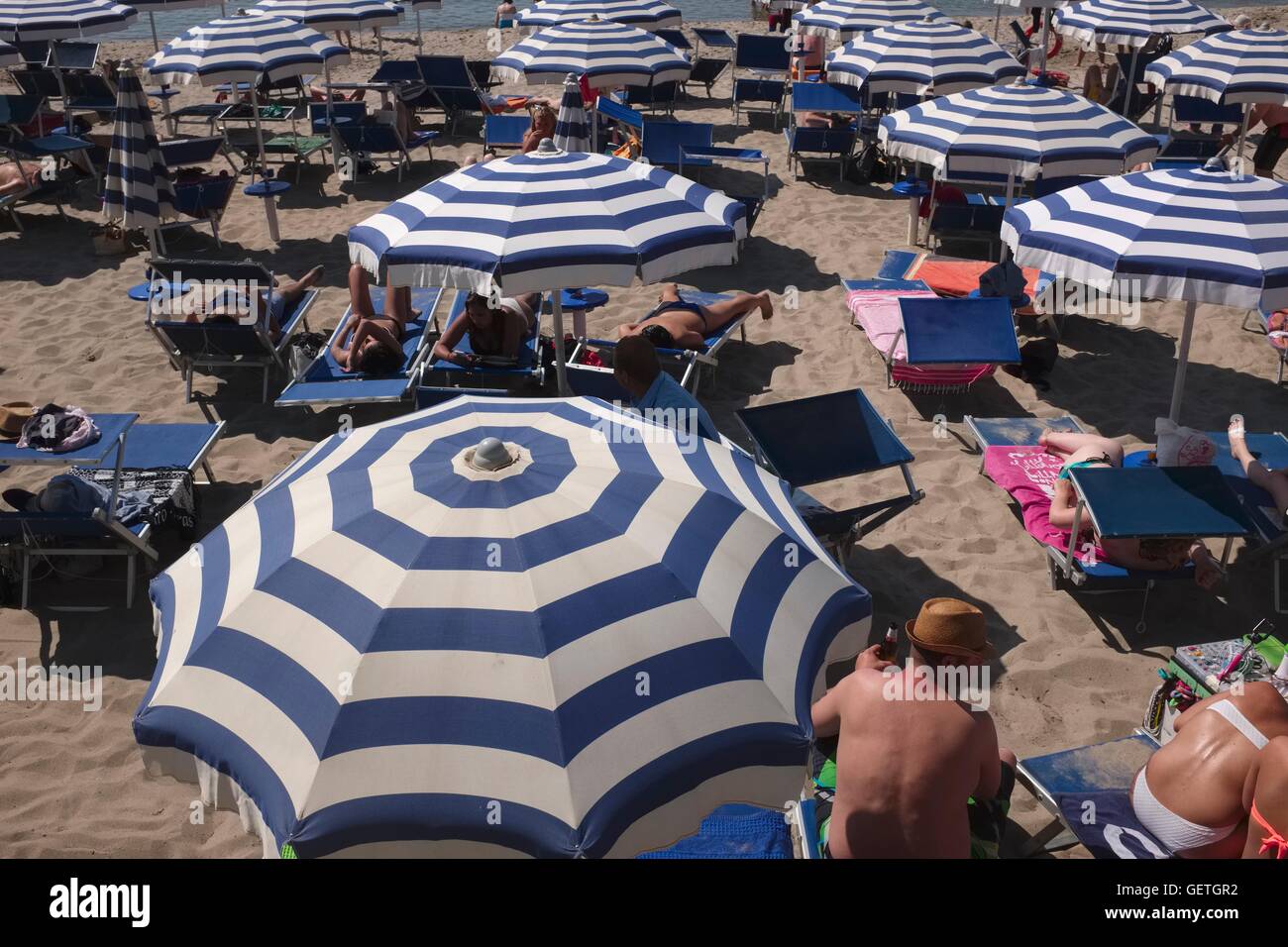 People sunbathing on beach with blue sunshades Stock Photo - Alamy