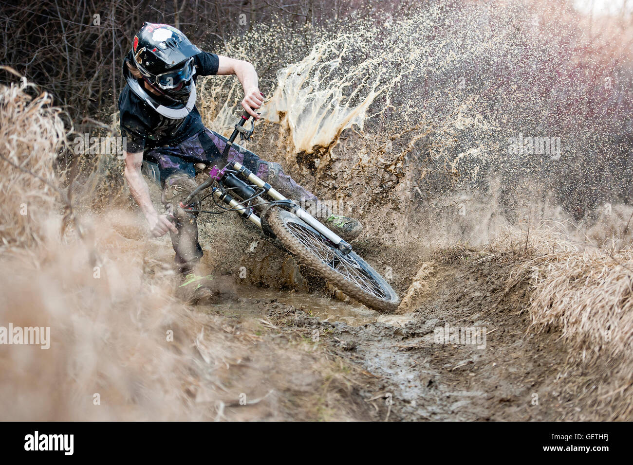 Mountainbiker rides on path in mud Stock Photo - Alamy