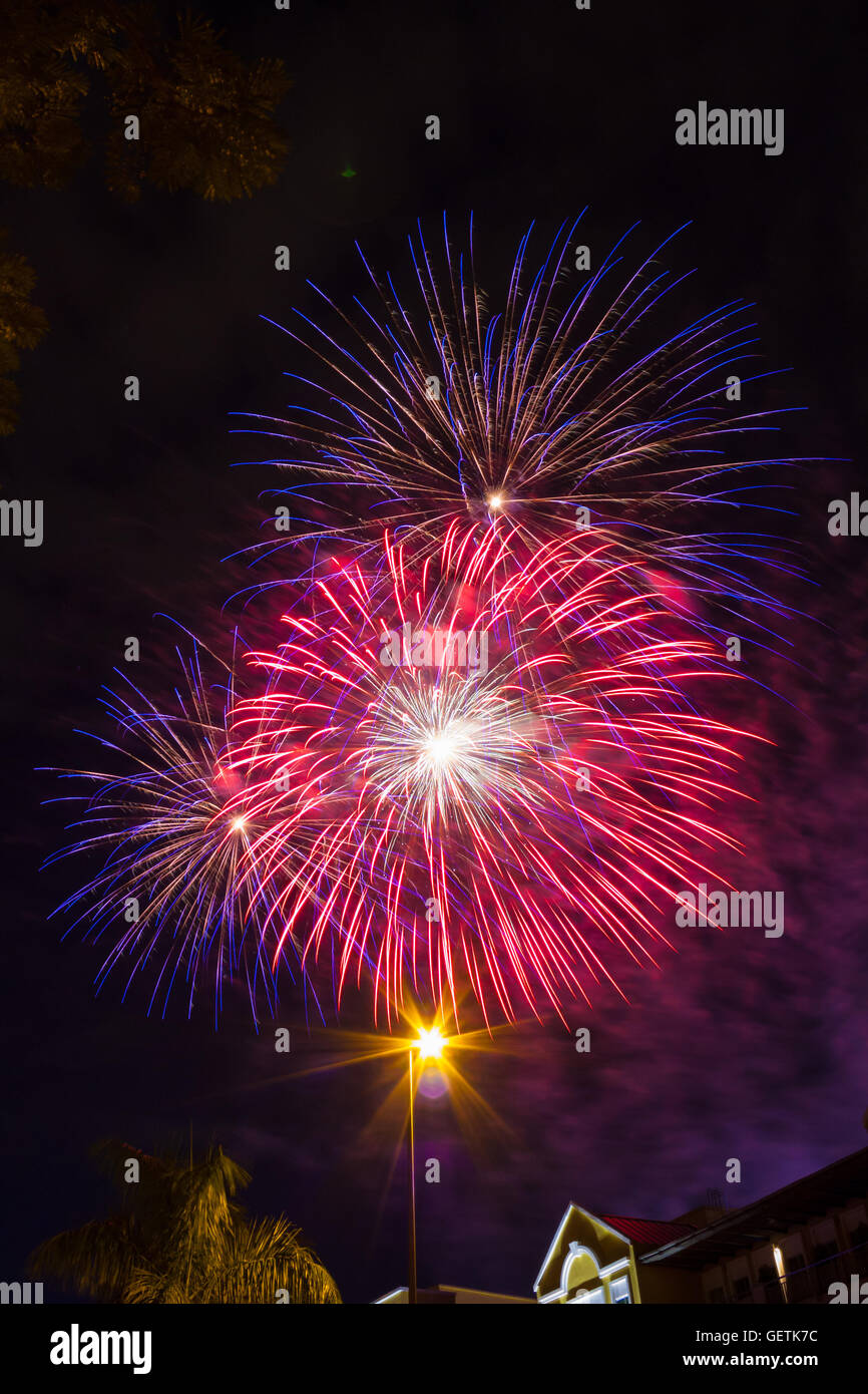 Isolated red blue fireworks burst above building Stock Photo - Alamy