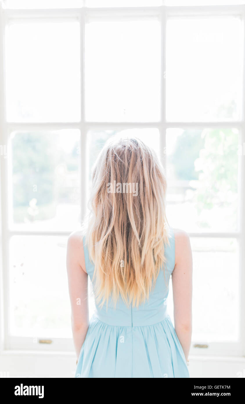 A blonde girl looking out of a window Stock Photo - Alamy