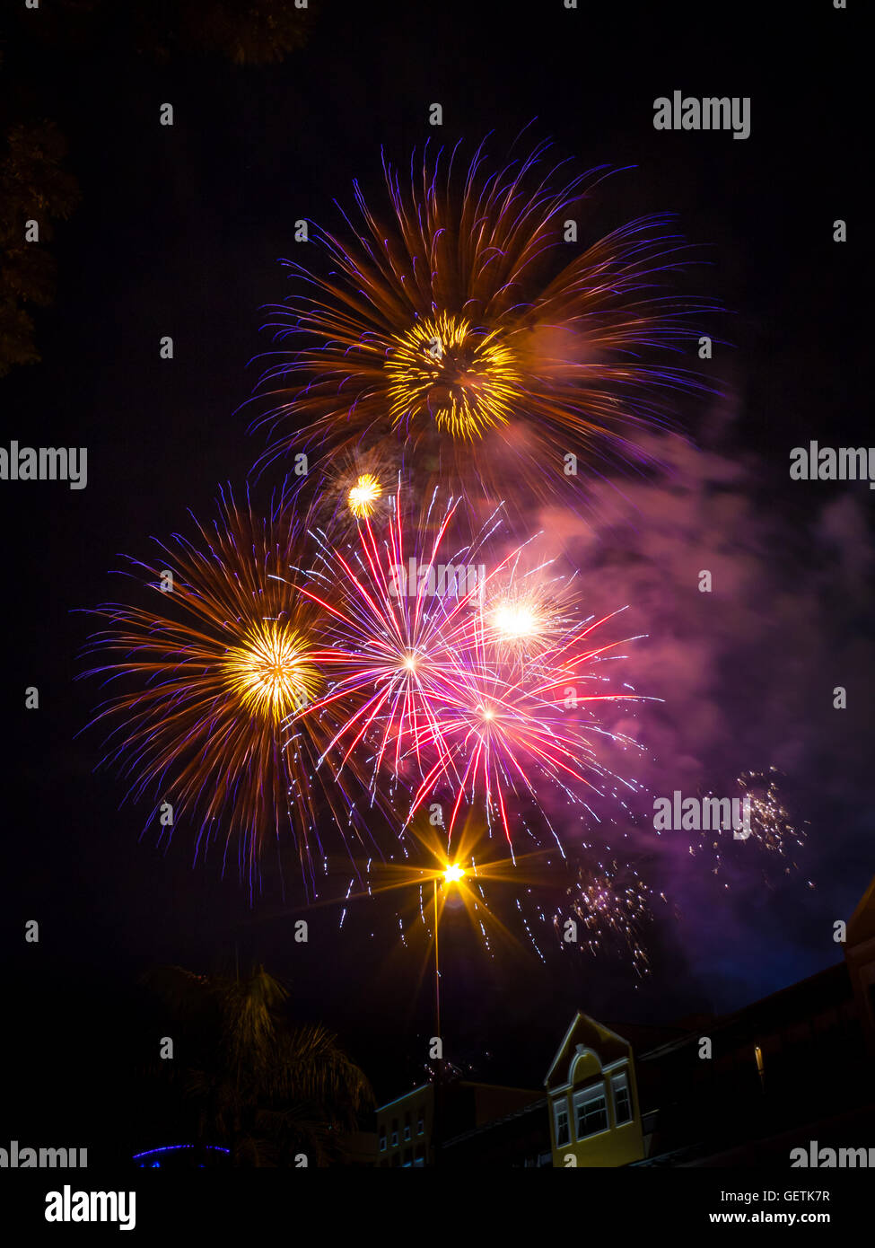 Isolated multi colored fireworks burst above building Stock Photo - Alamy