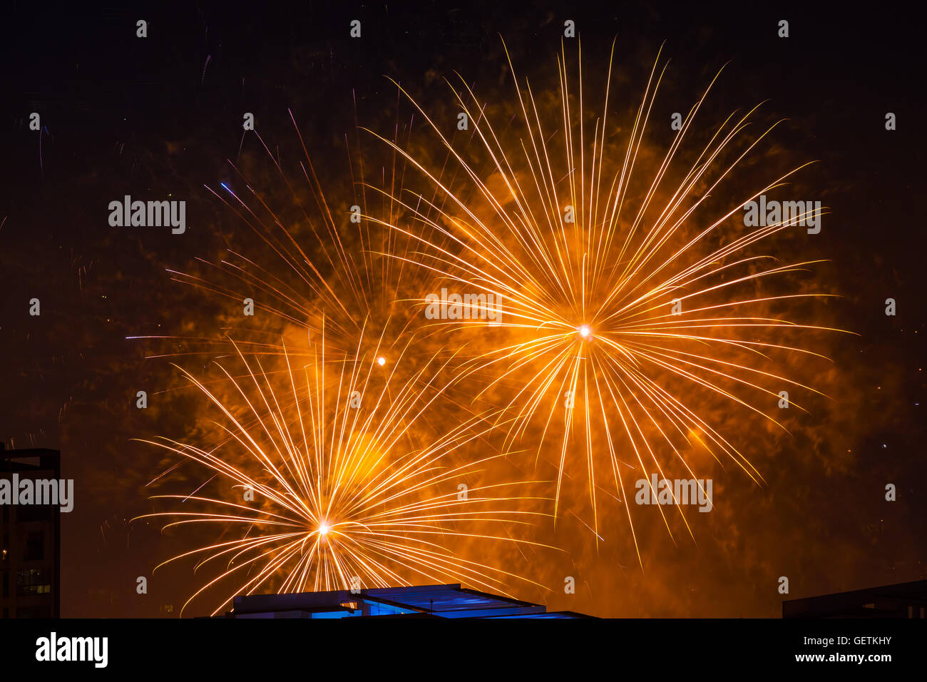 Multiple orange fireworks burst above buildings Stock Photo - Alamy