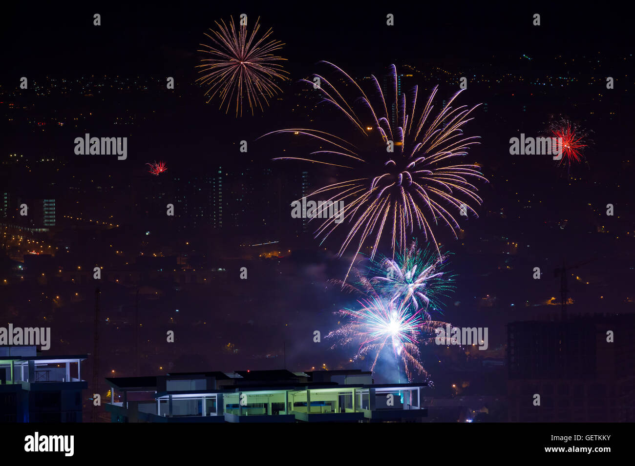Multiple fireworks burst above building and city Stock Photo - Alamy