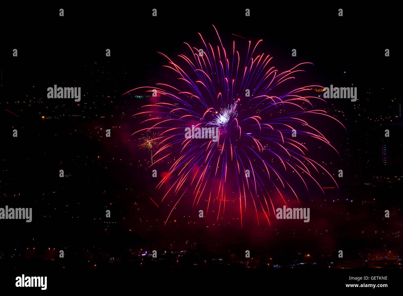 red blue fireworks burst over city lights Stock Photo - Alamy