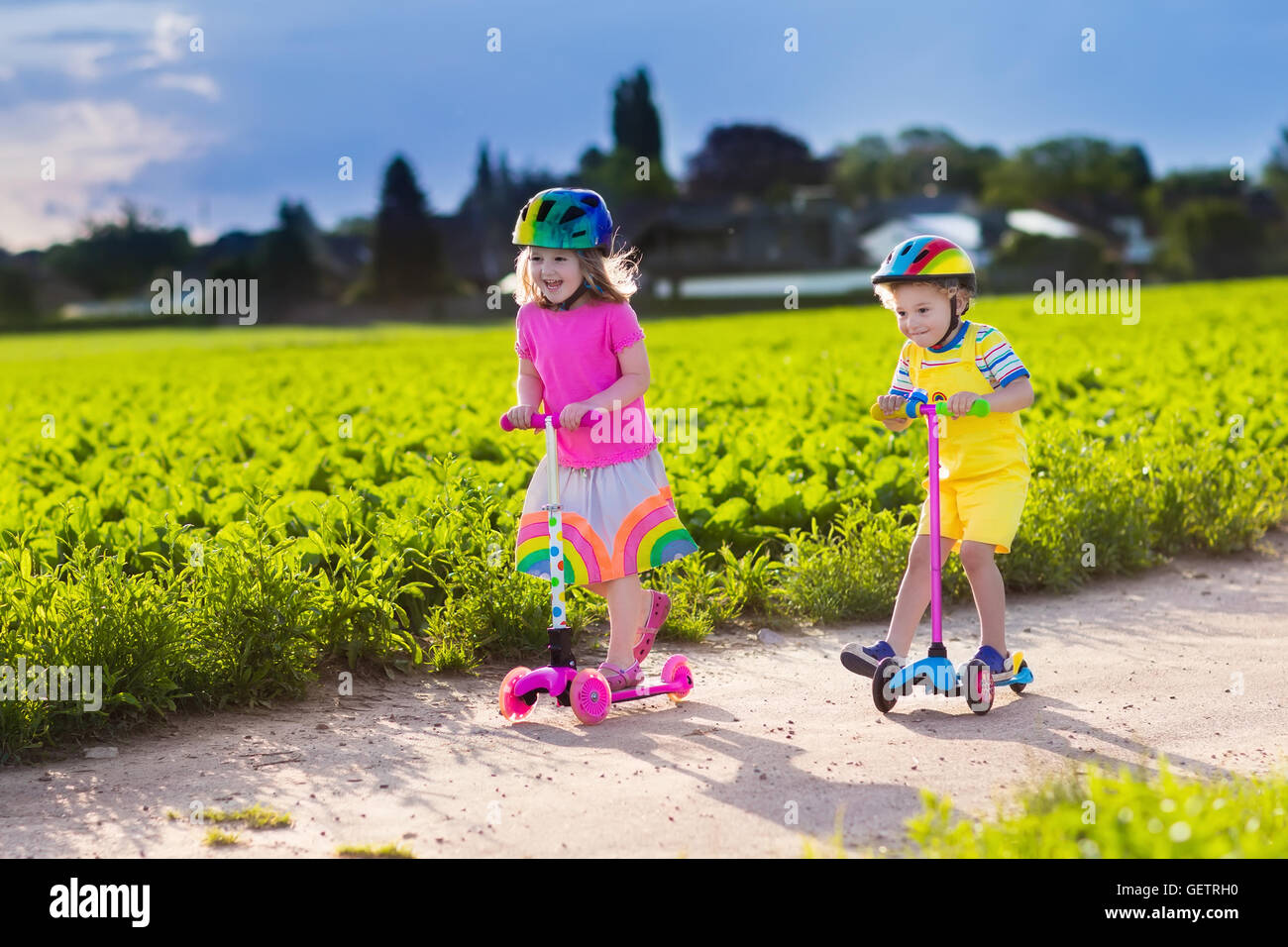 Children learn to ride scooter in a park on sunny summer day ...