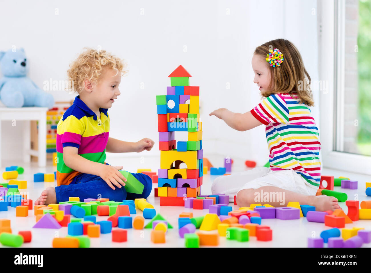 Happy preschool age children play with colorful plastic toy blocks ...