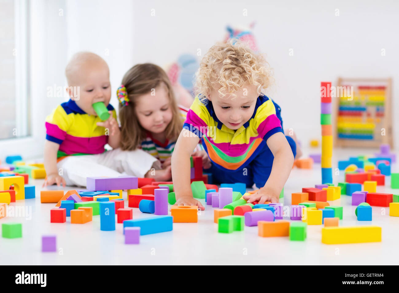 Happy preschool age children play with colorful plastic toy blocks ...