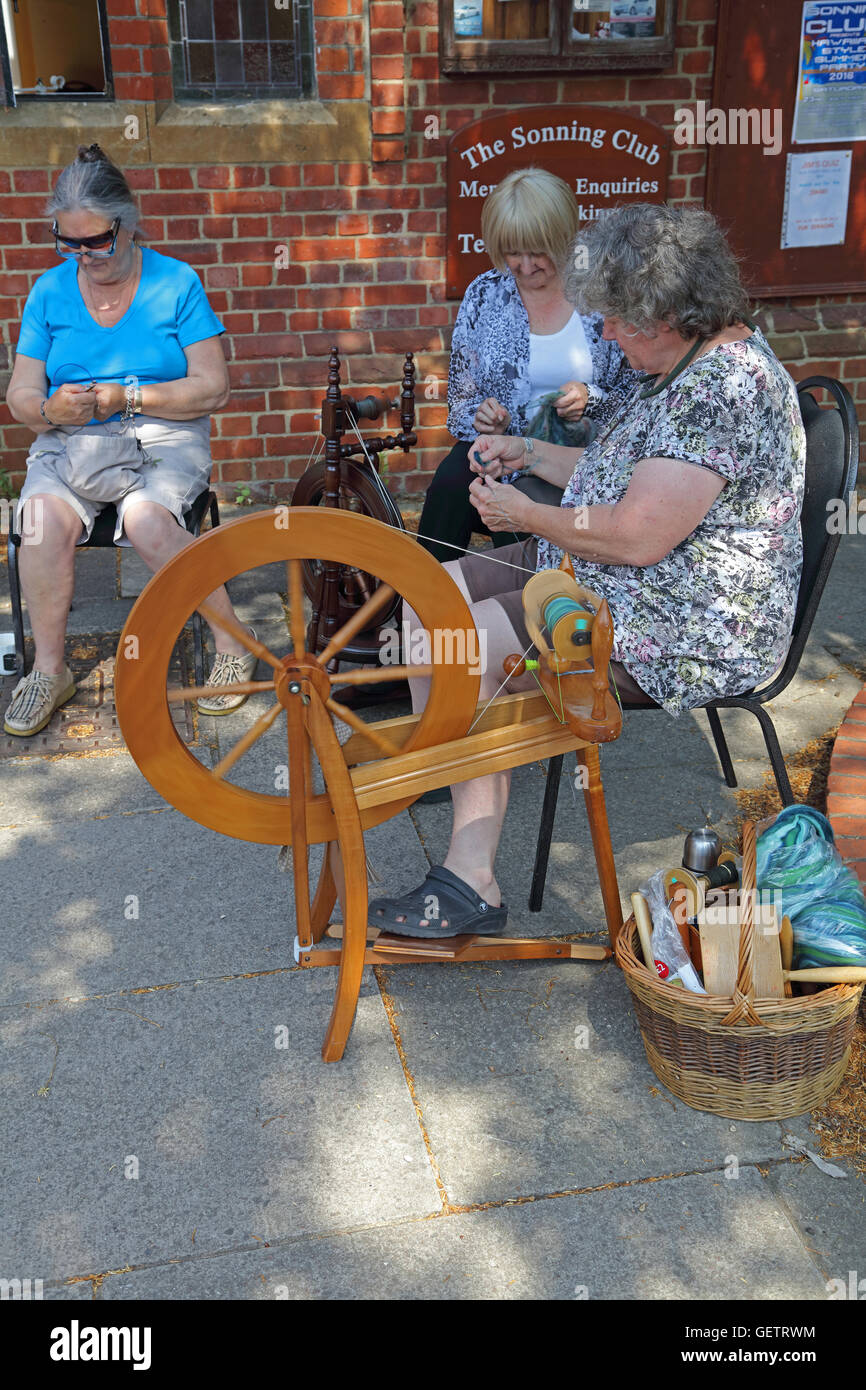 Two ladies sitting by their spinning wheels "teasing" out the wool ...