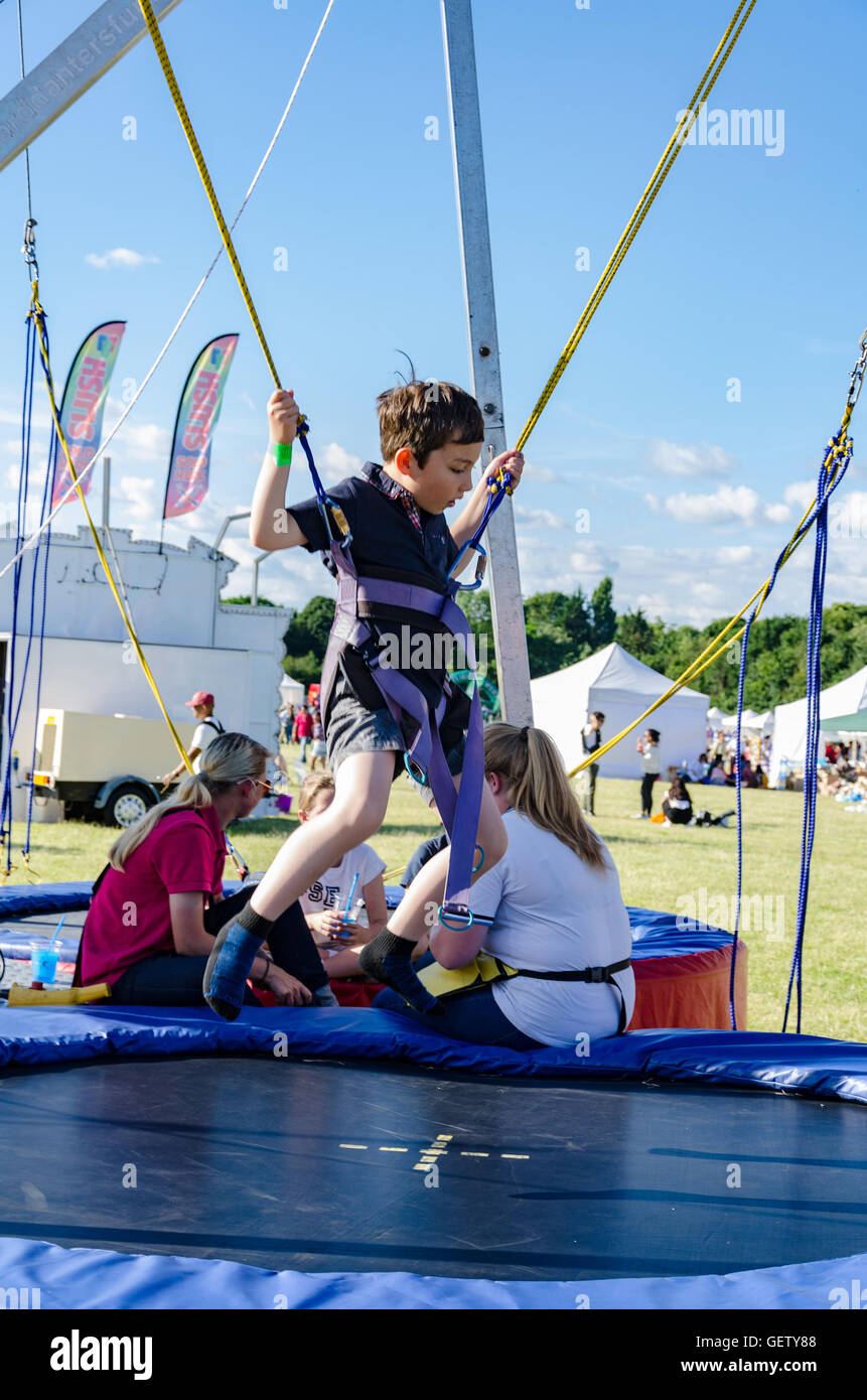 A young boy has fun jumping on a bungee trampoline at a fairground ...