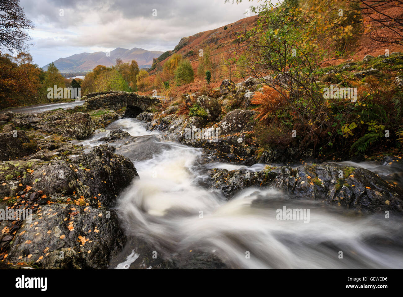 A river flowing towards an old stone bridge in the Lake District Stock ...