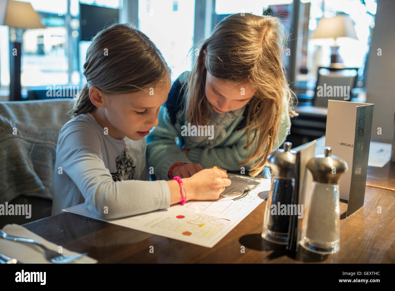 Two children looking at a menu in a restaurant Stock Photo - Alamy