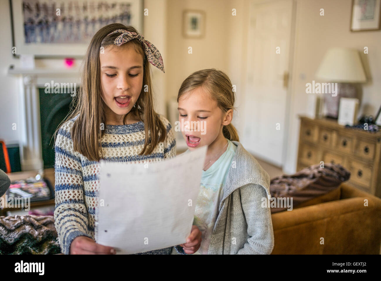 Two children singing from a song sheet Stock Photo - Alamy