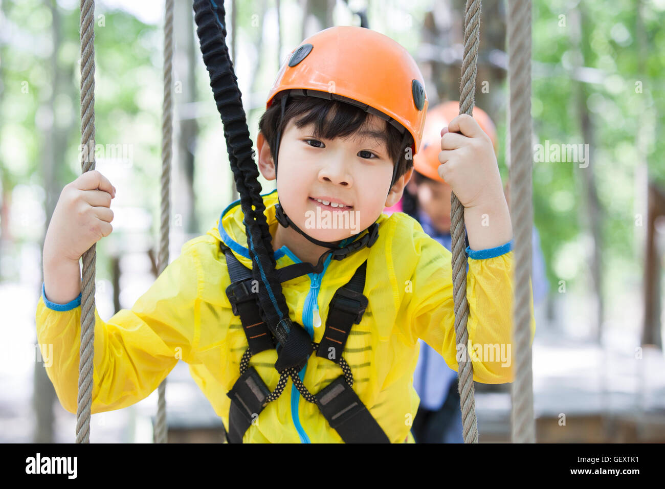 Little Chinese boy playing in tree top adventure park Stock Photo - Alamy