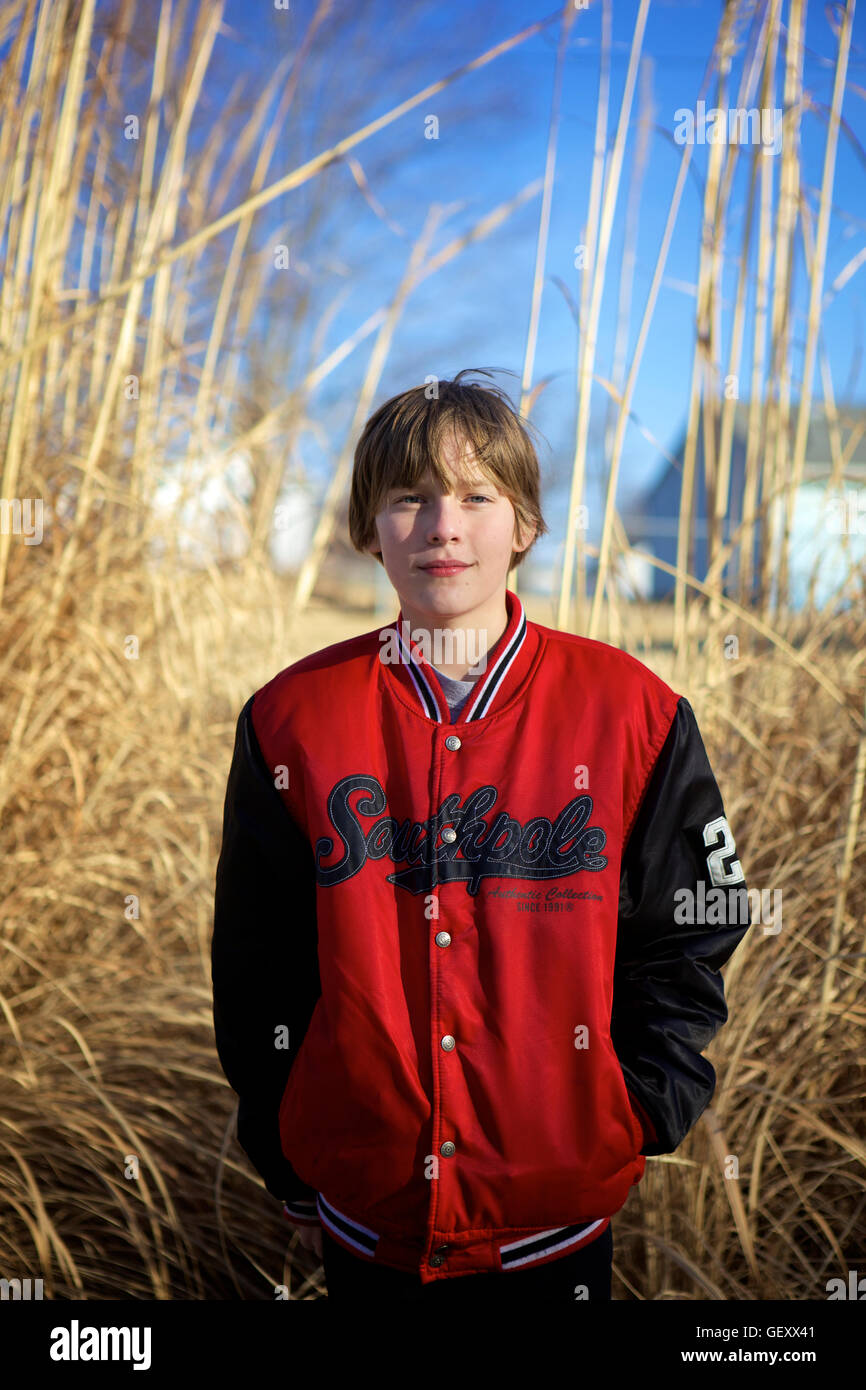 Young boy looking at camera In a cornfield beside a farm In the midwest ...