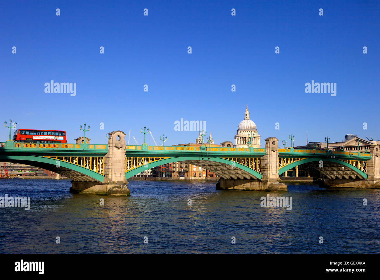 Red London bus on Southwark Bridge with St Paul's and River Thames ...
