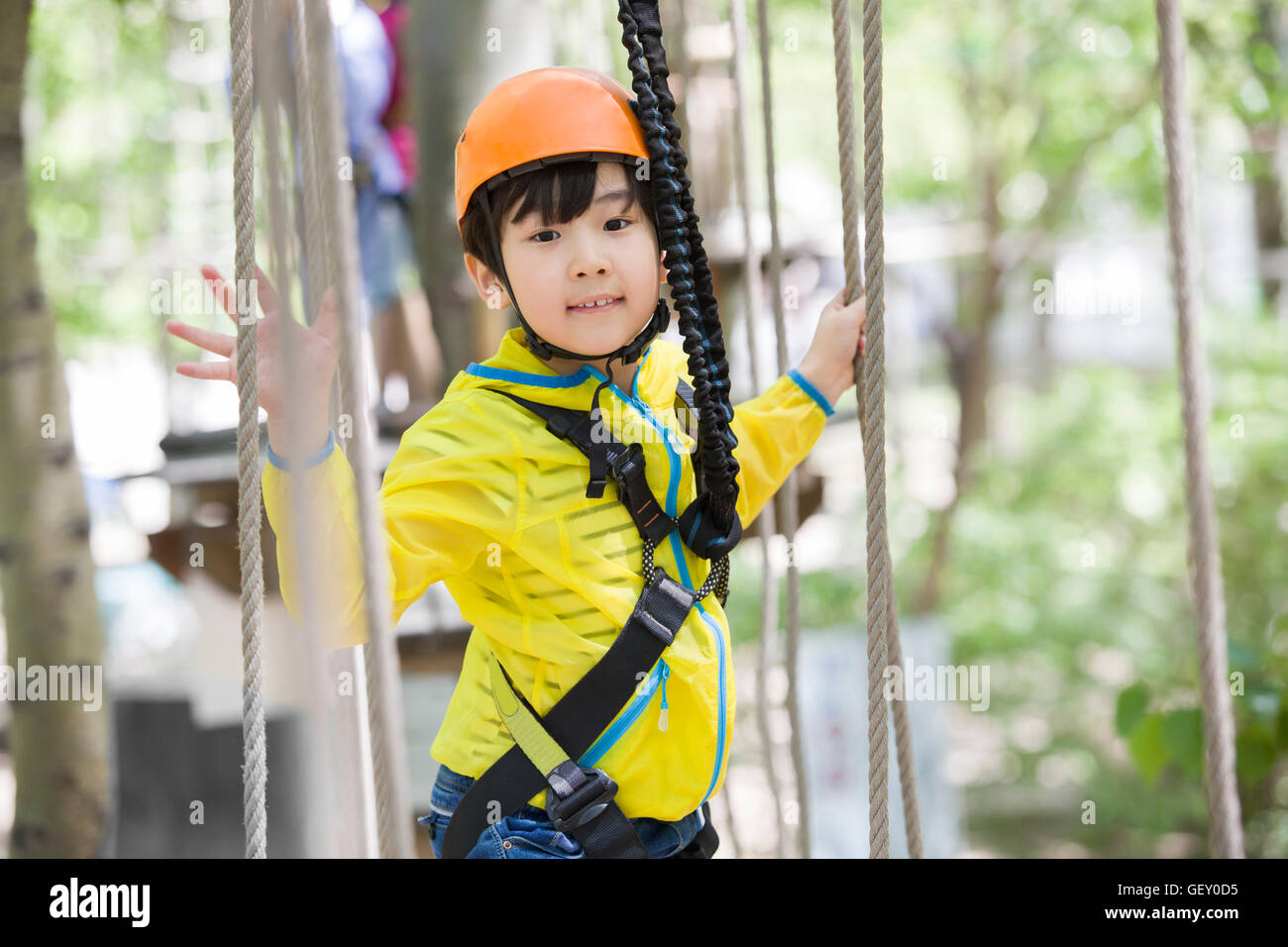 Little Chinese boy playing in tree top adventure park Stock Photo - Alamy
