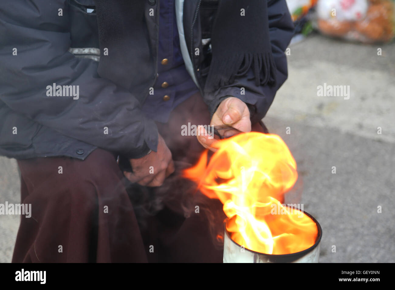 poor man in the street using a mobile phone and heats up with the ...