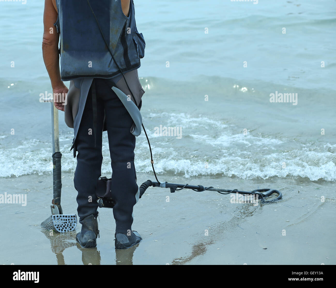 Man with metal detector to find lost objects under the sand of the sea ...