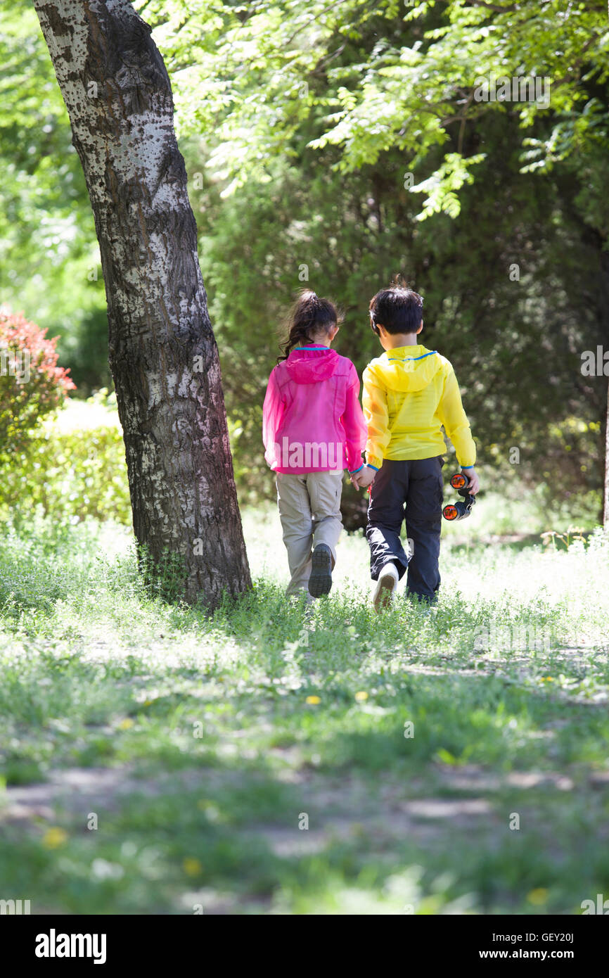 Happy Chinese children holding hands walking in woods Stock Photo - Alamy