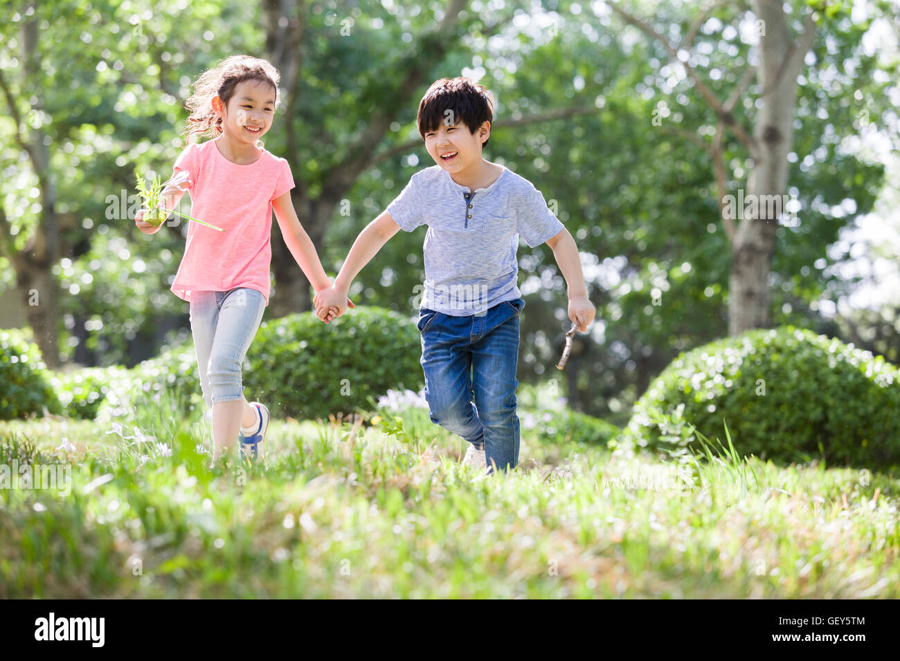 Happy Chinese children holding hands running in woods Stock Photo - Alamy