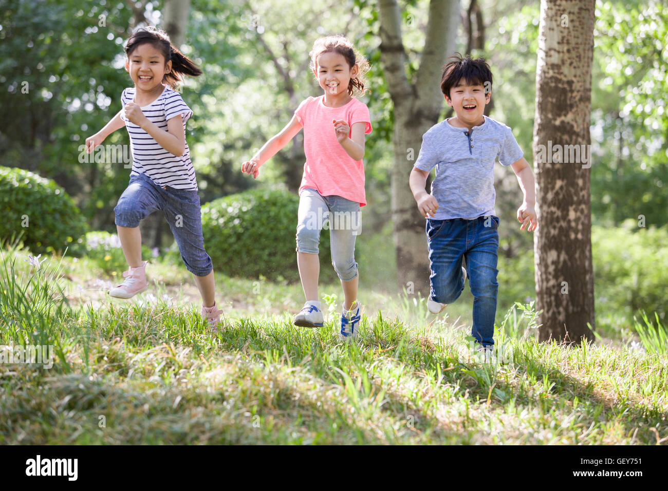 Happy Chinese children running in woods Stock Photo - Alamy