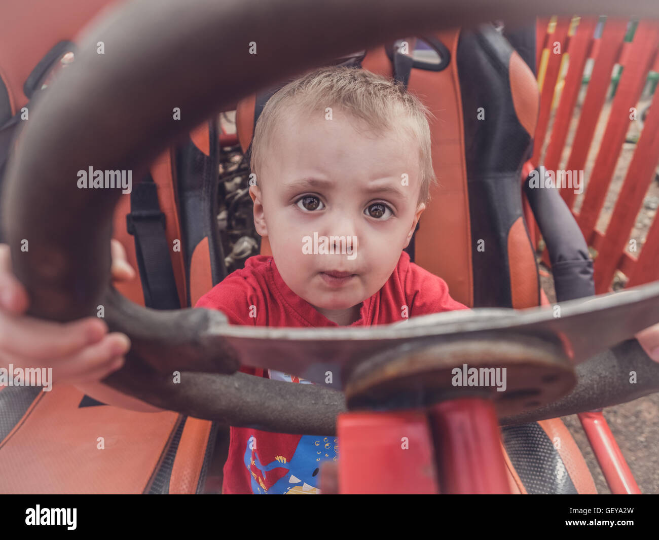 Little boy sitting behind the wheel of an immobile car truck in a ...